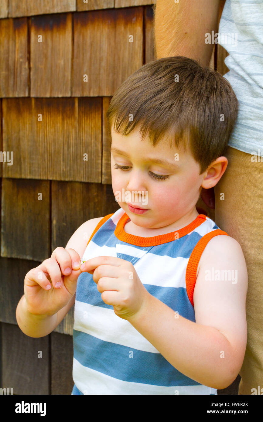 A boy is playing with an object outdoors while standing with his father ...