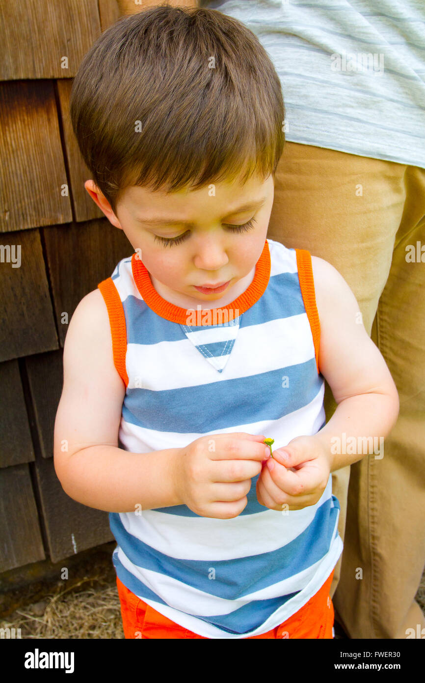 A boy is playing with an object outdoors while standing with his father ...