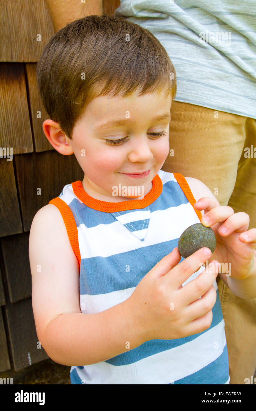 A boy is playing with an object outdoors while standing with his father ...