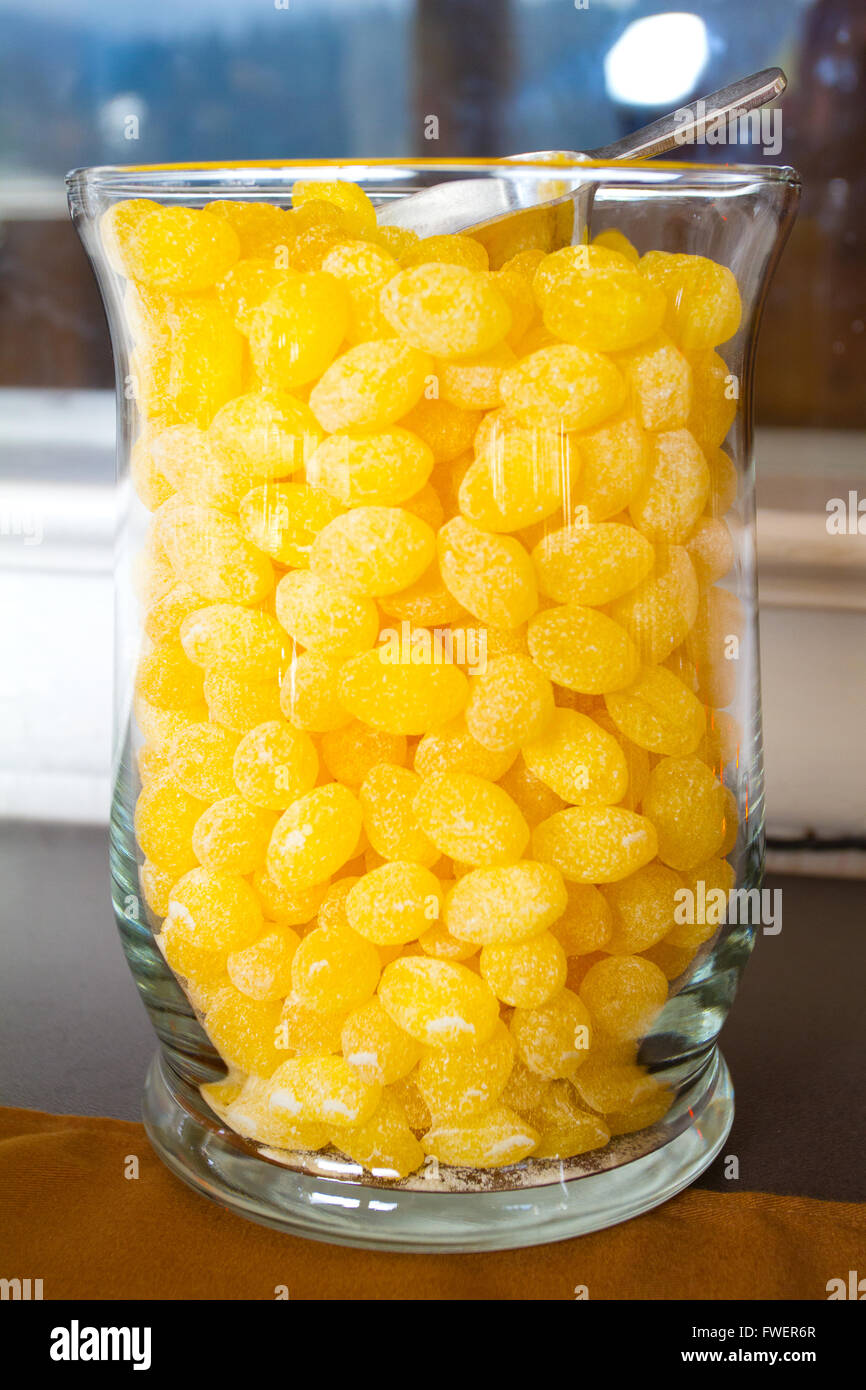 Yellow lemon drops are in a glass vase at a wedding at a candy bar ...