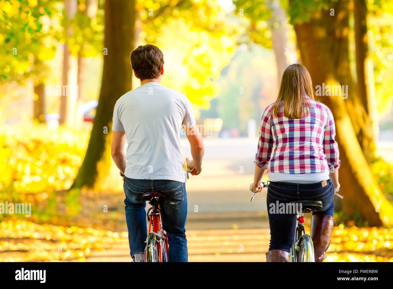 A couple rides their bikes together along a bicycle path in the fall ...