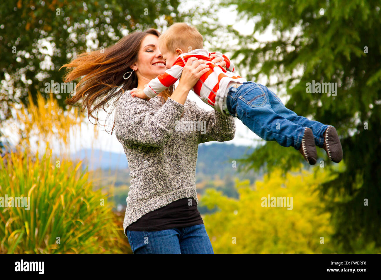 A woman spins her child around while holding him in the air in this ...