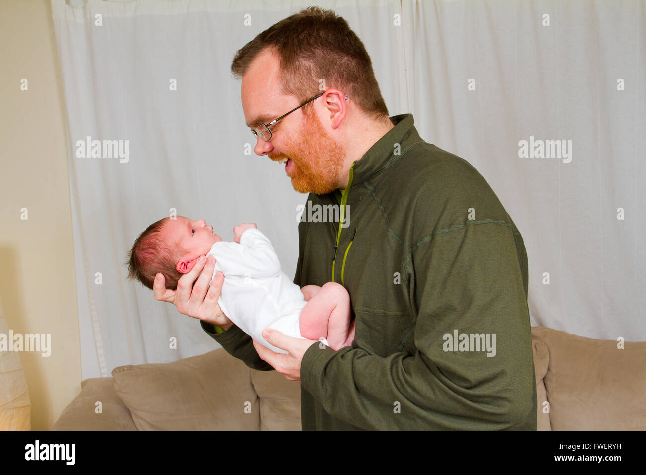 Lifestyle portrait of a dad or father with his newborn baby boy in his ...