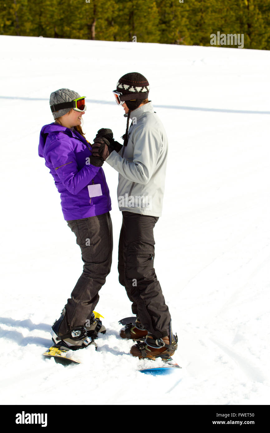 A couple snowboards down some groomed ski runs at a mountain resort ...