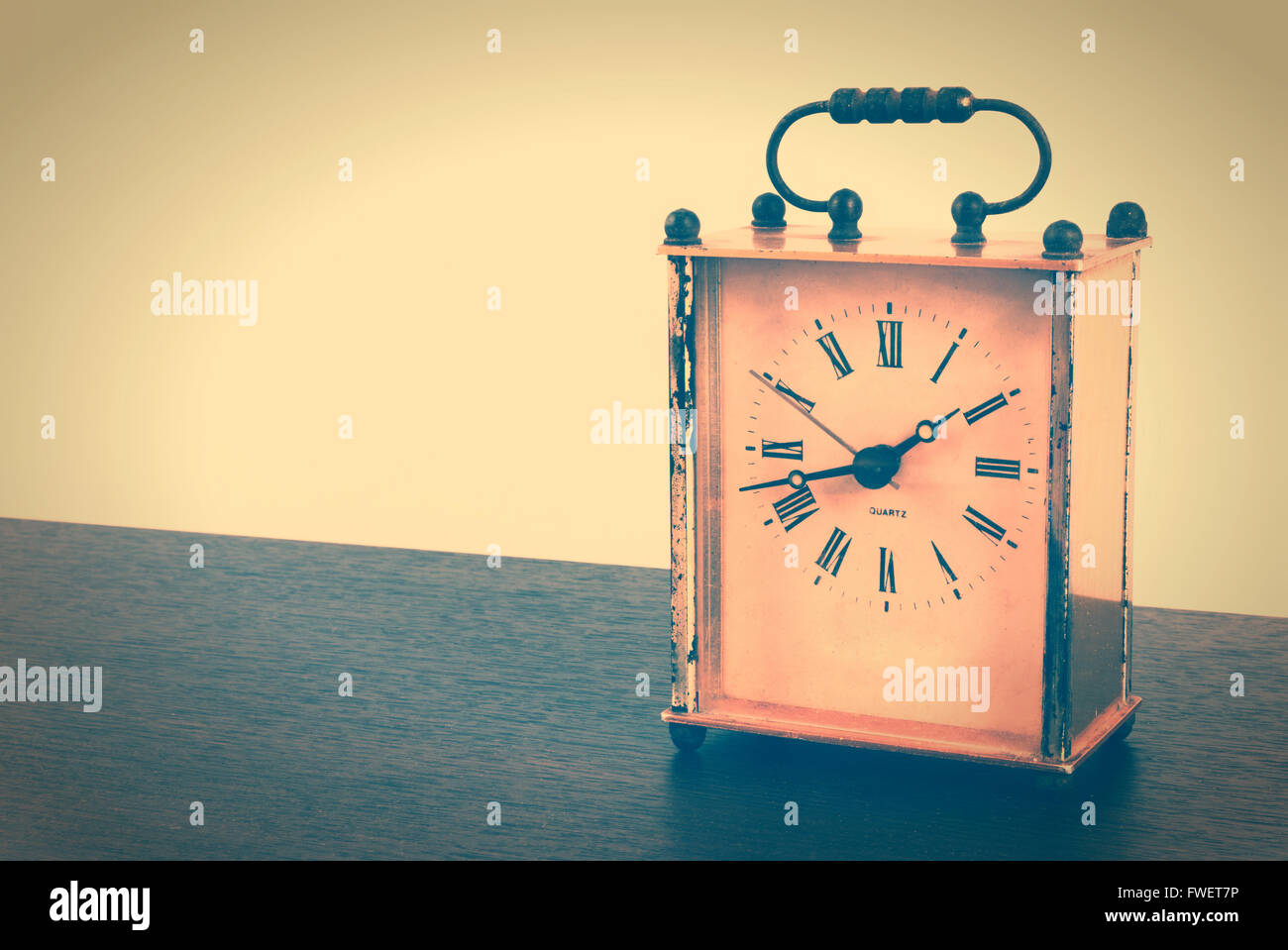 Retro styled image of vintage square table clock on a wooden table ...