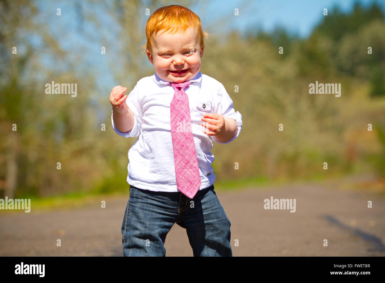 A one year old boy taking some of his first steps outdoors on a path ...