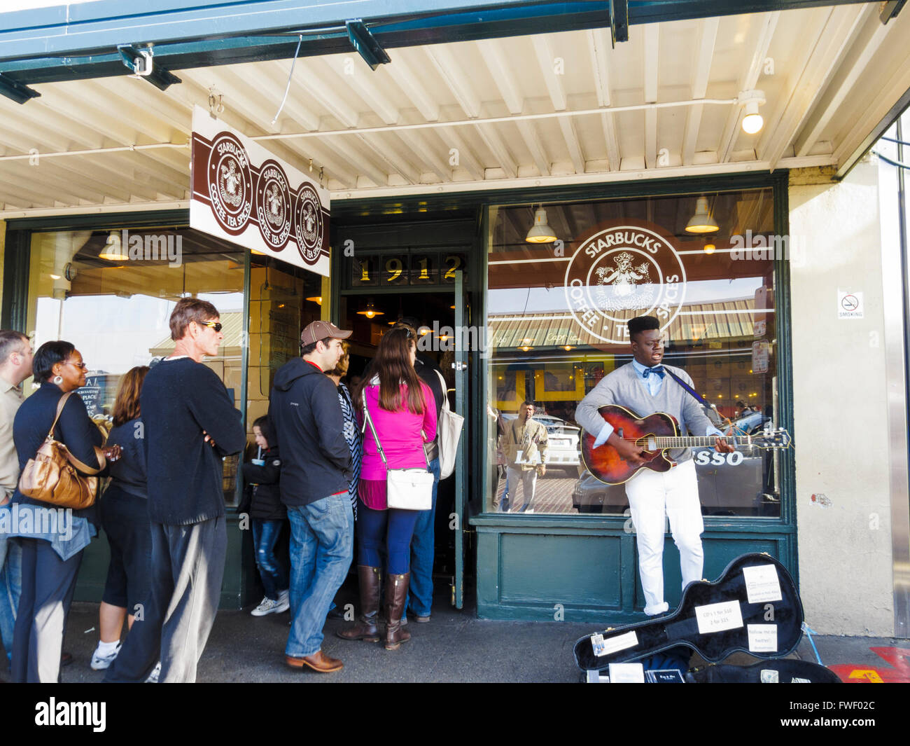Street artists and customer queue in front of first Starbucks coffee ...