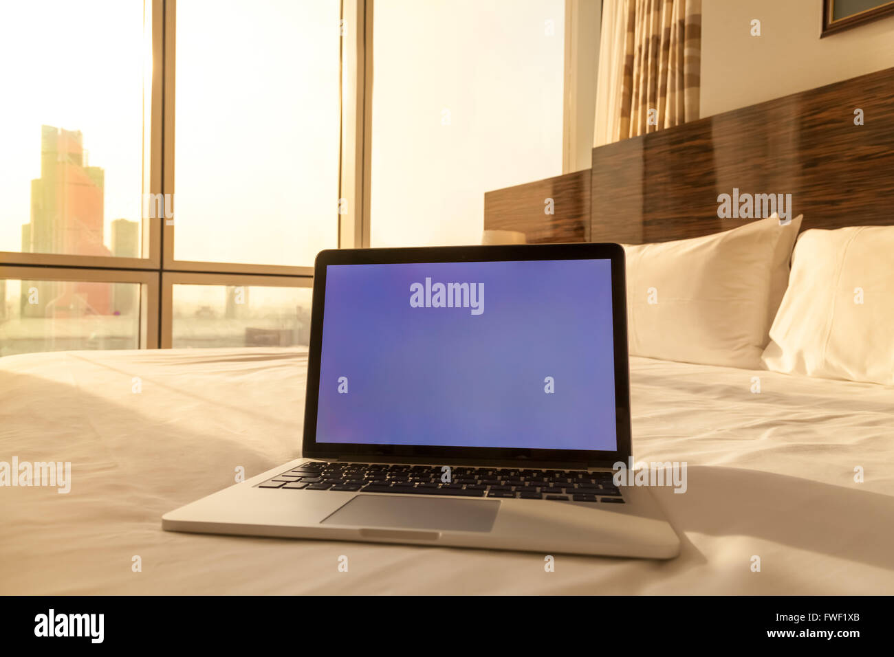 Laptop computer on white bed sheets in cozy hotel room with copy space ...
