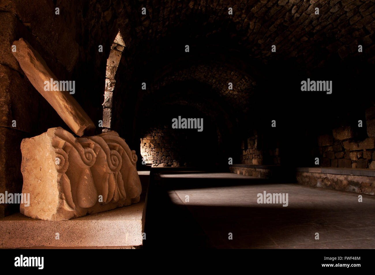 Carved stone in the interior hall with stone walls of old ruined castle ...
