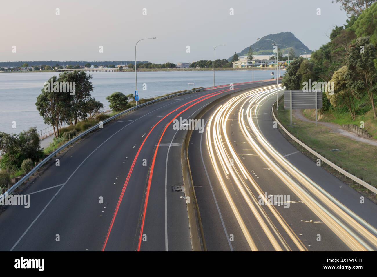Highway light streams along Takitimu Drive at dusk looking north with ...