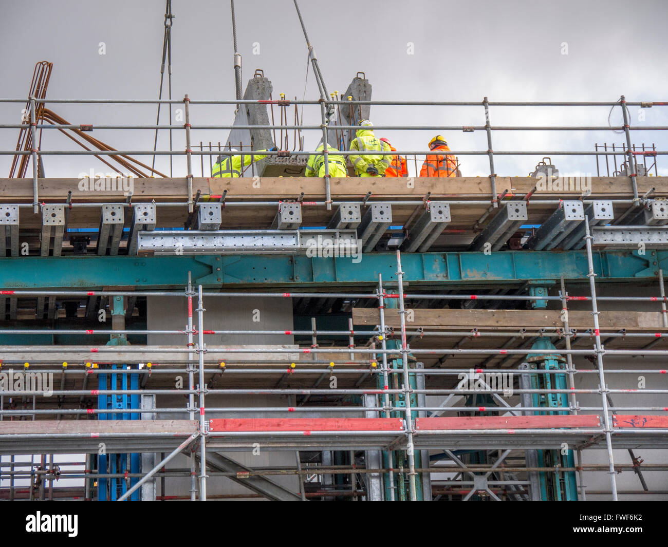 Construction workers fitting concrete pillars using a large crane Stock ...