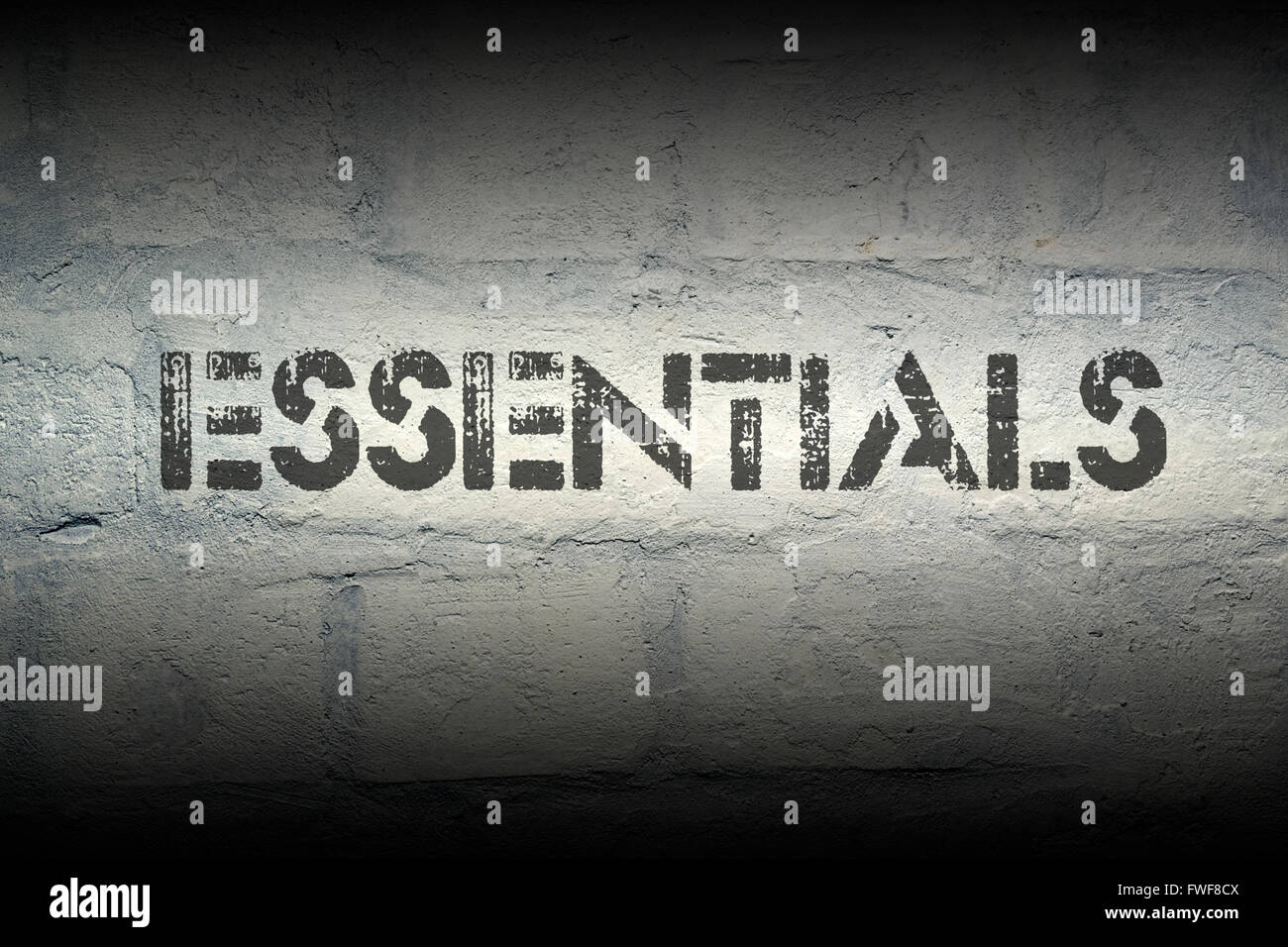 essentials stencil print on the grunge white brick wall Stock Photo - Alamy