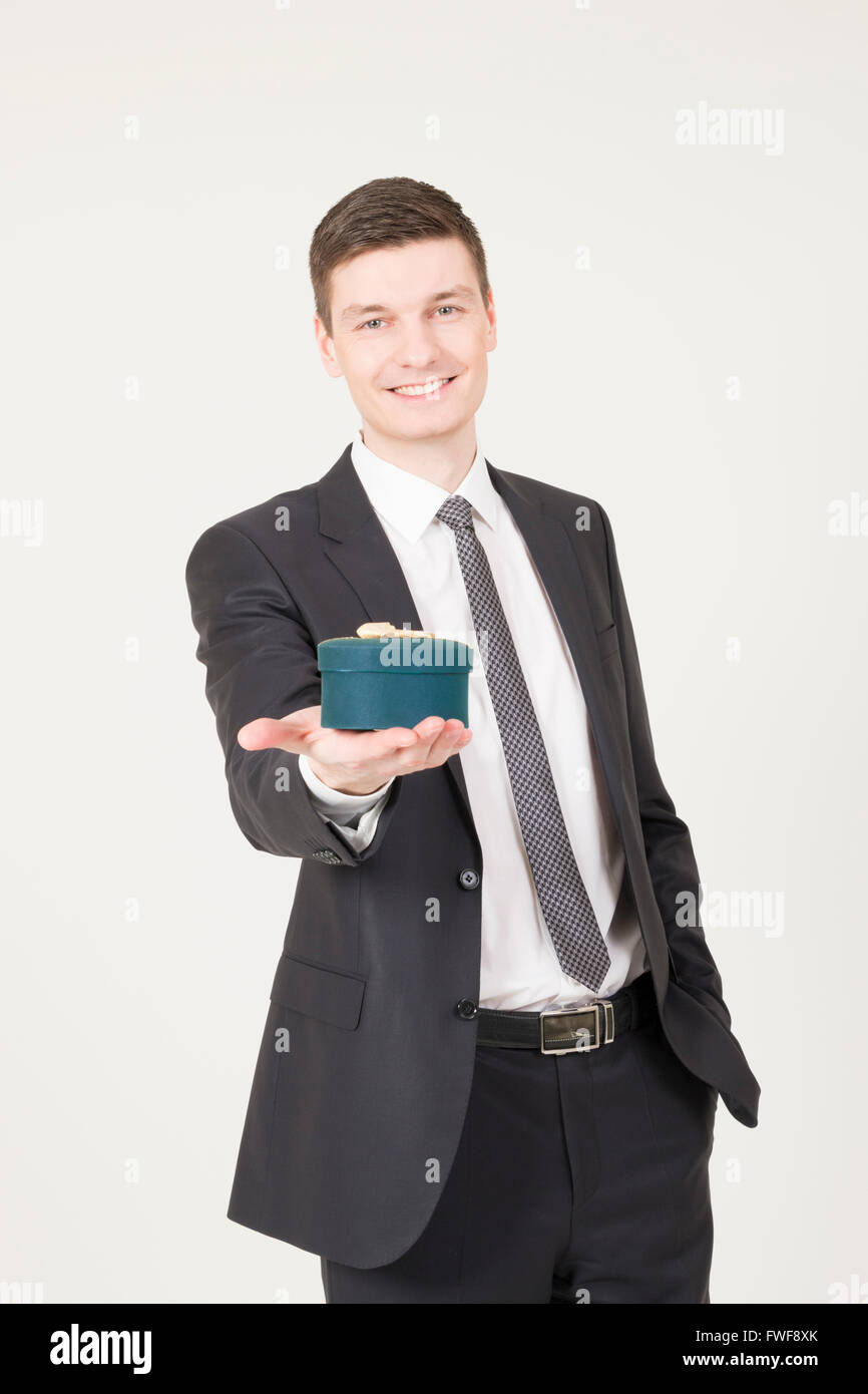 Handsome young man with gift box on the grey background Stock Photo - Alamy