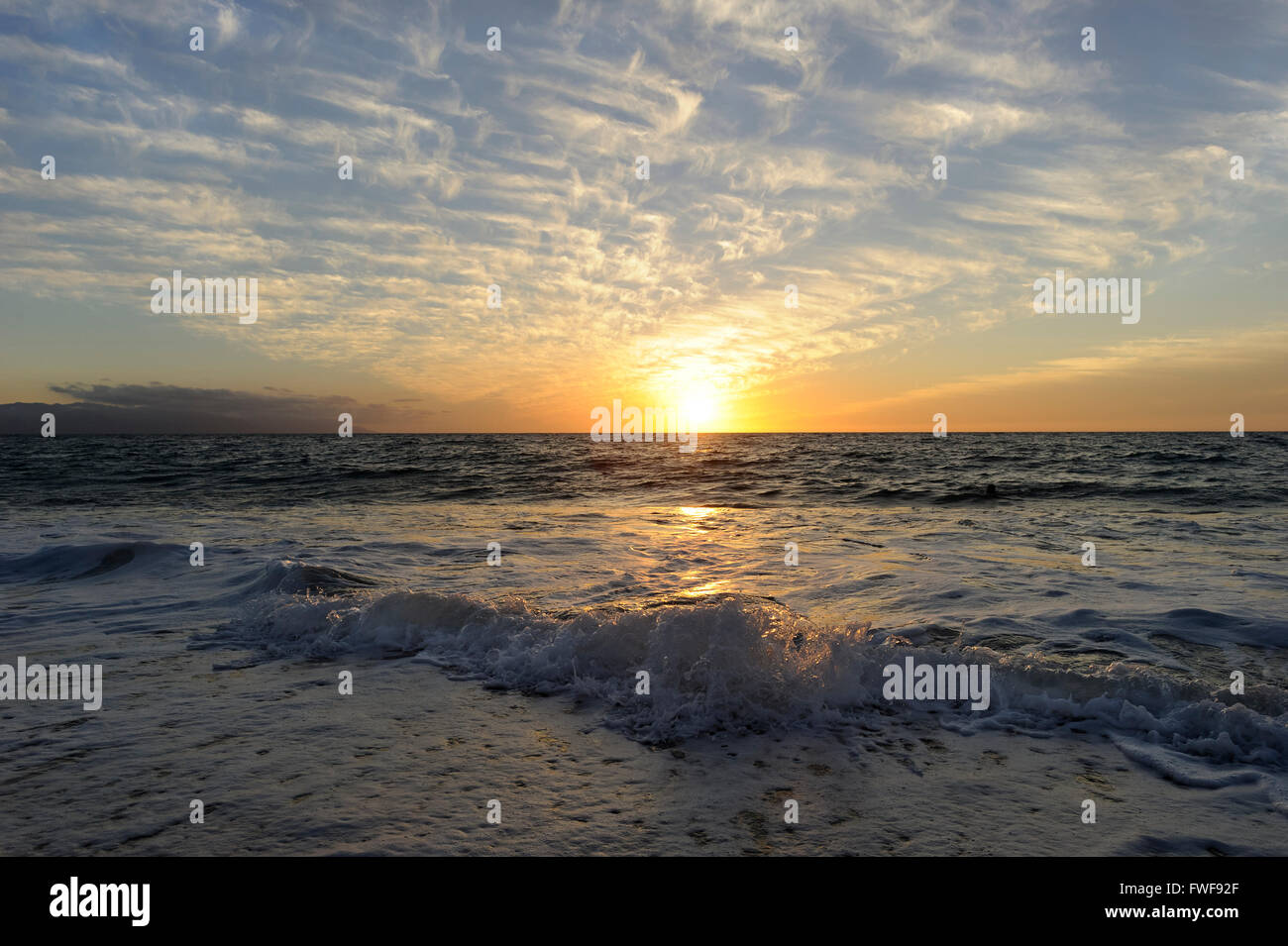 Ocean sunset is a brightly lit golden blue seascape with a gentle wave ...