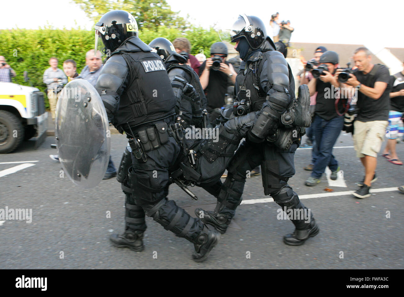 Armed police officers watch Loyalists during trouble in north Belfast ...