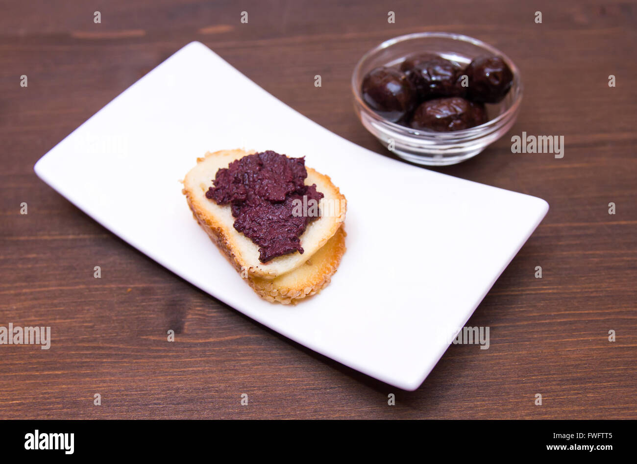 Slice of bread with olive paste on wooden table Stock Photo - Alamy
