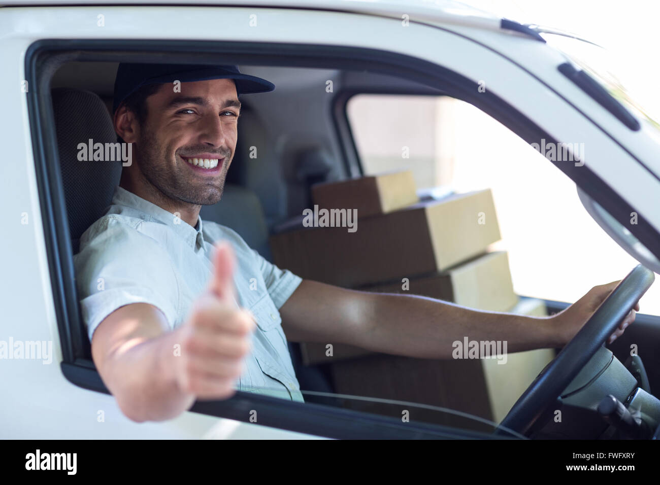Delivery man showing thumbs up while driving van Stock Photo - Alamy