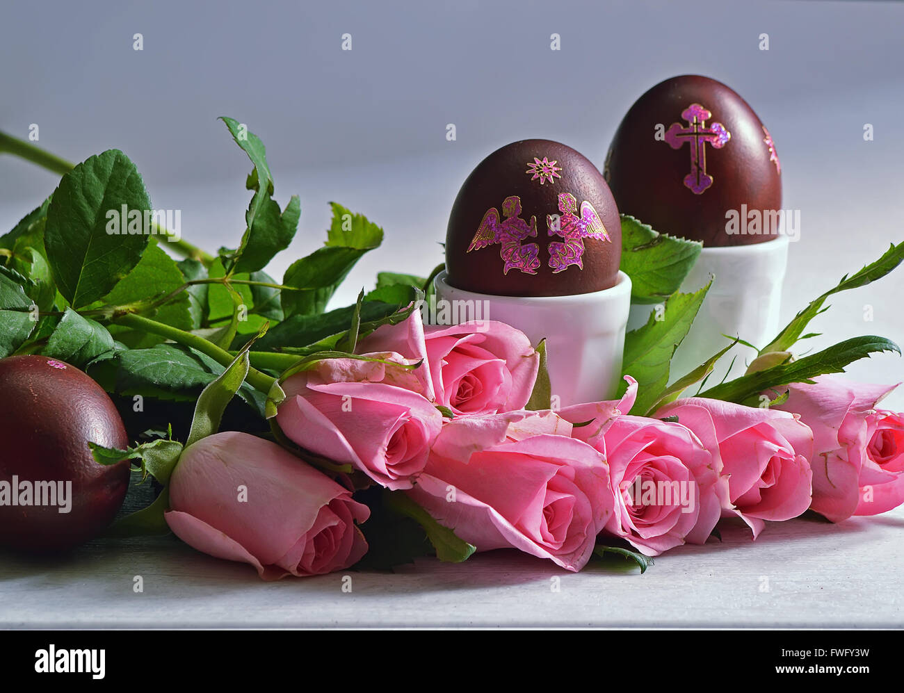 Easter still life with colored eggs in the stands and roses on the ...