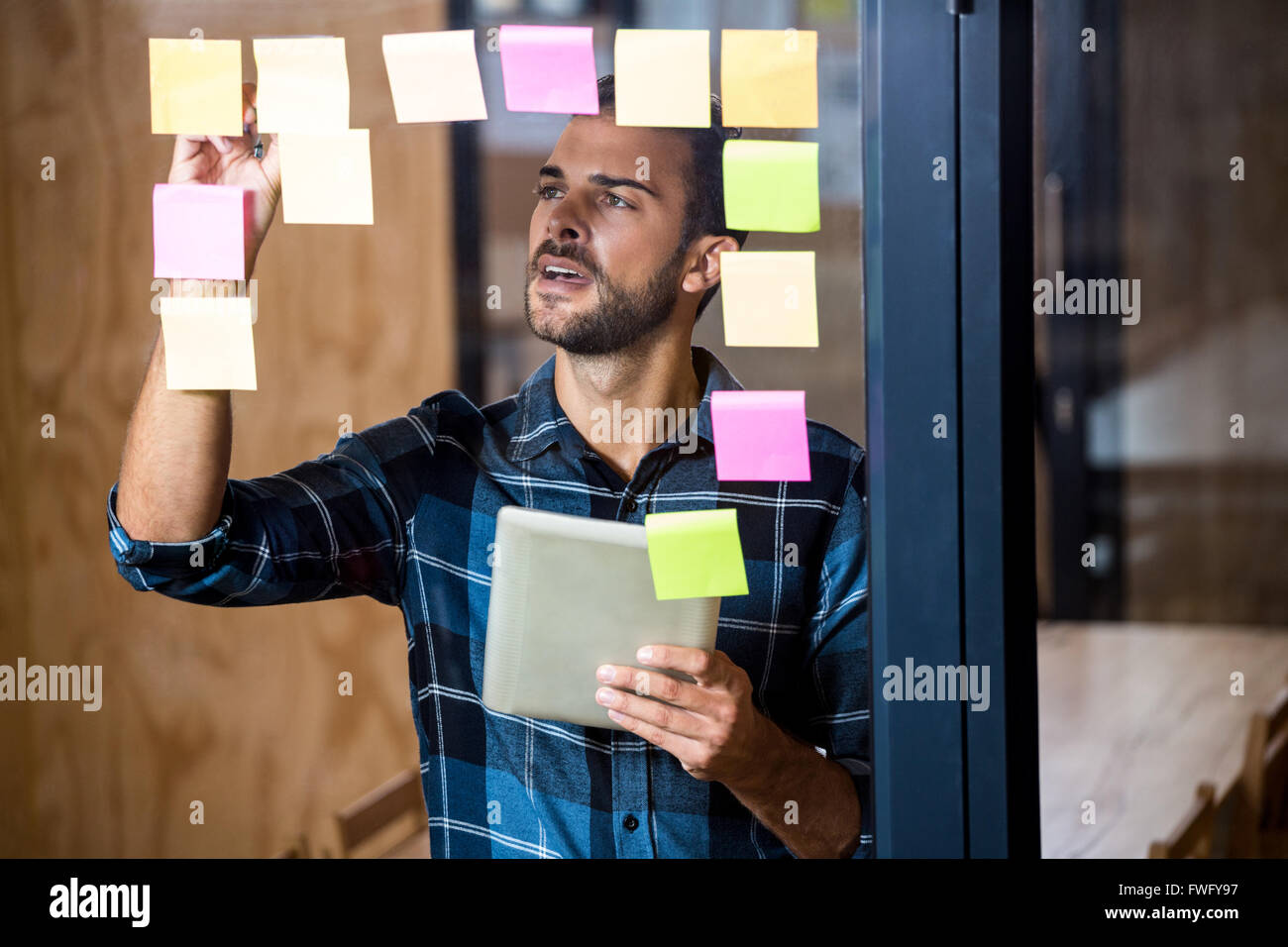 Man using digital tablet while writing on sticky notes Stock Photo - Alamy