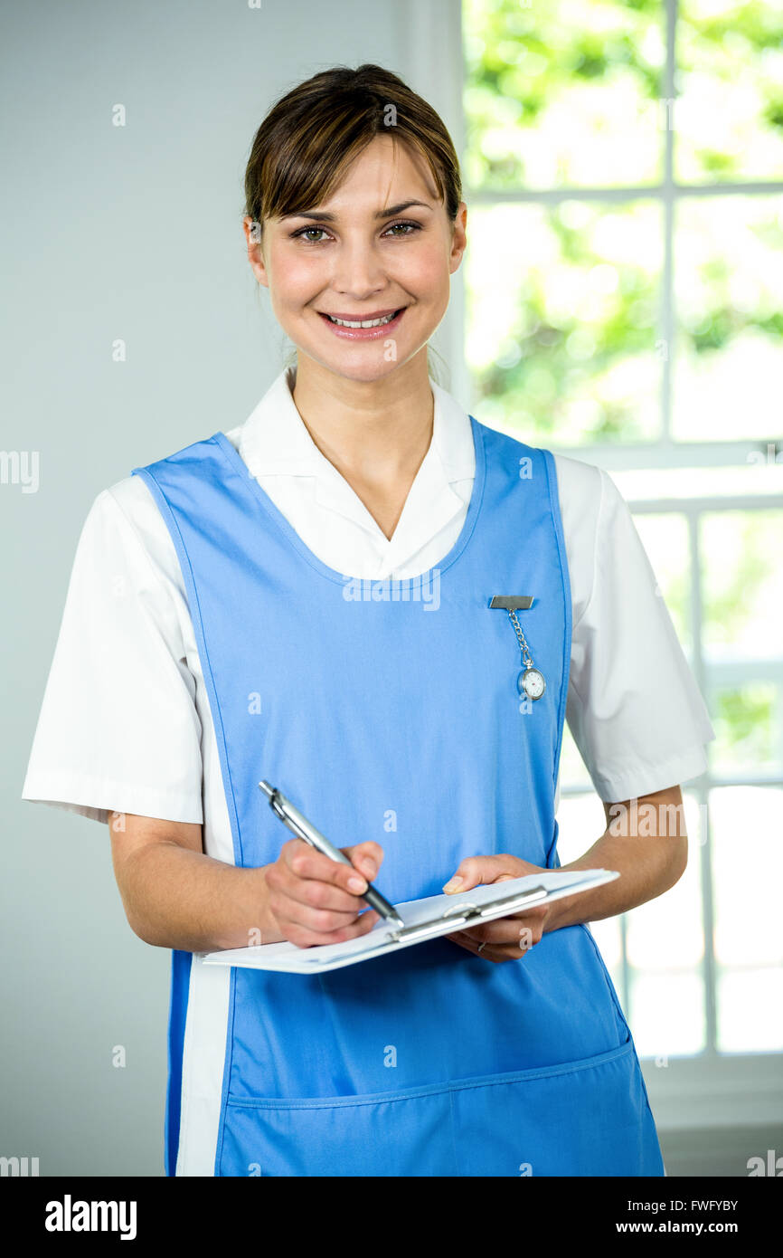 Portrait of smiling nurse writing on clipboard Stock Photo - Alamy
