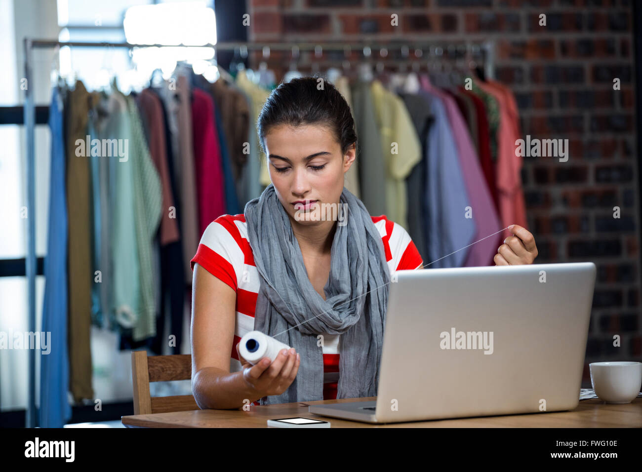 Woman with a laptop holding a thread reel Stock Photo - Alamy