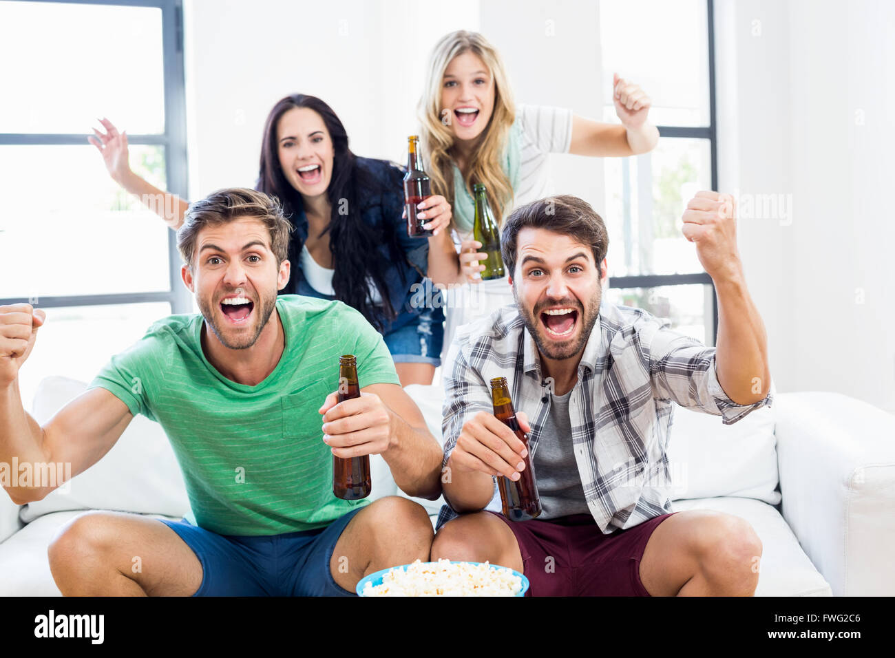 Excited friend holding beer bottles Stock Photo - Alamy