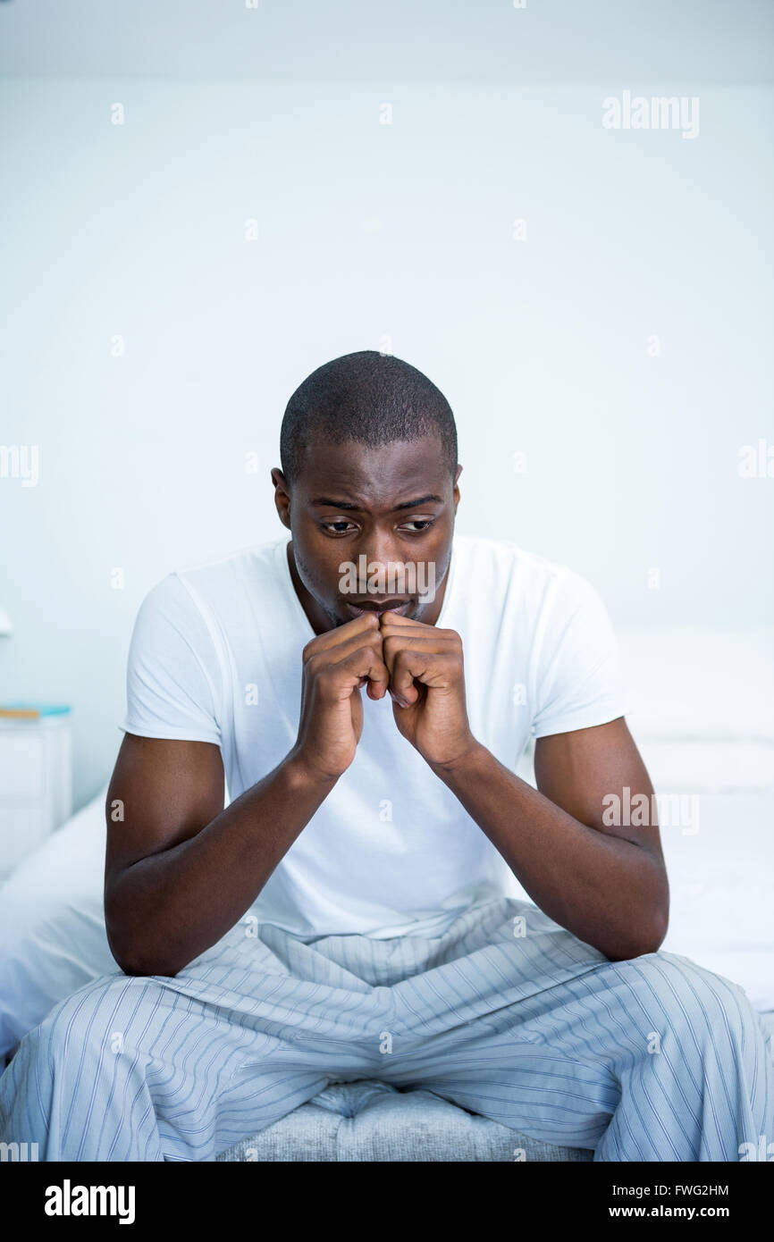 Tensed young man sitting on bed Stock Photo - Alamy