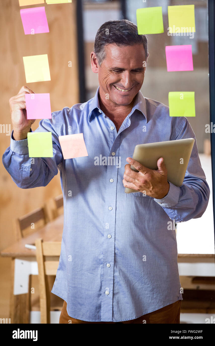 Man using digital tablet while writing on sticky notes Stock Photo - Alamy