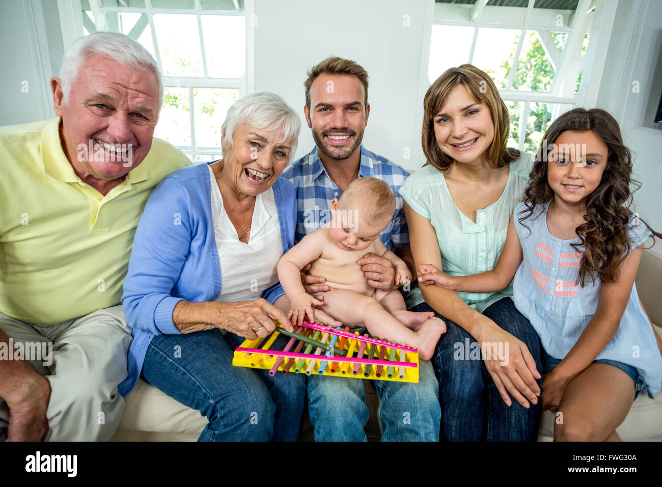 Happy multi-generation family sitting on sofa at home Stock Photo - Alamy