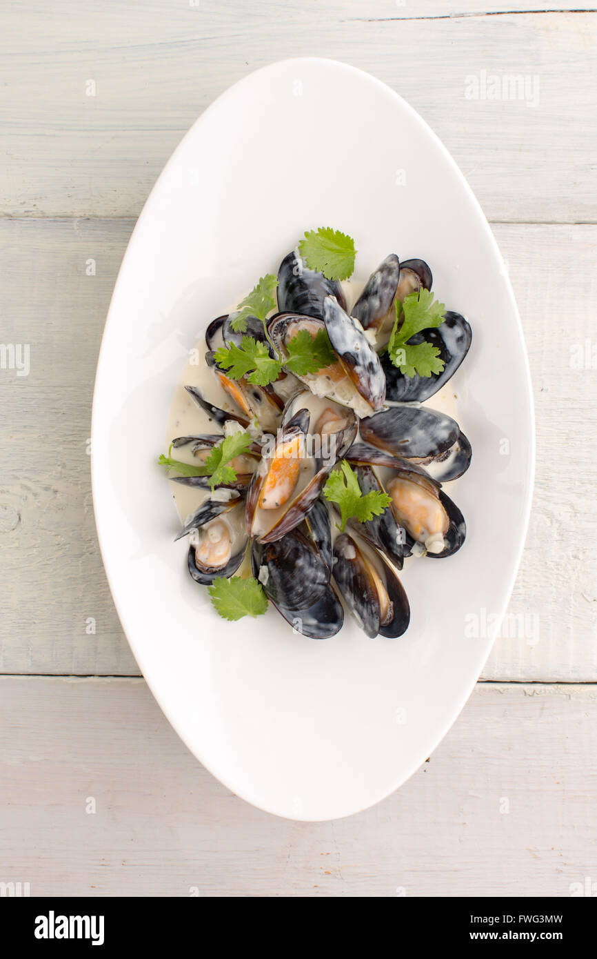 Mussels in a plate on white wooden background Stock Photo - Alamy