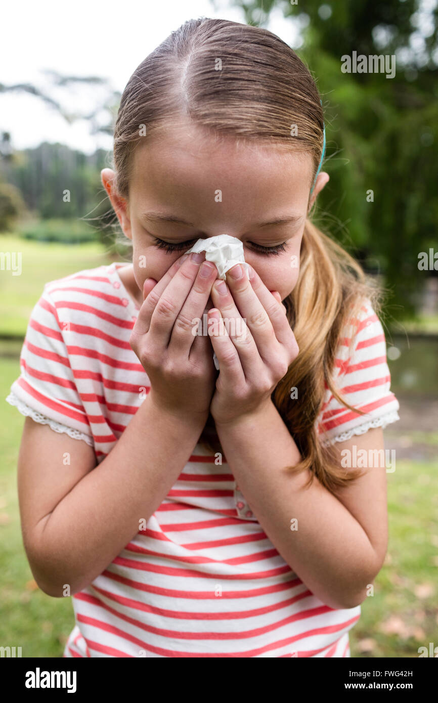 Sick girl sneezing in the park Stock Photo - Alamy