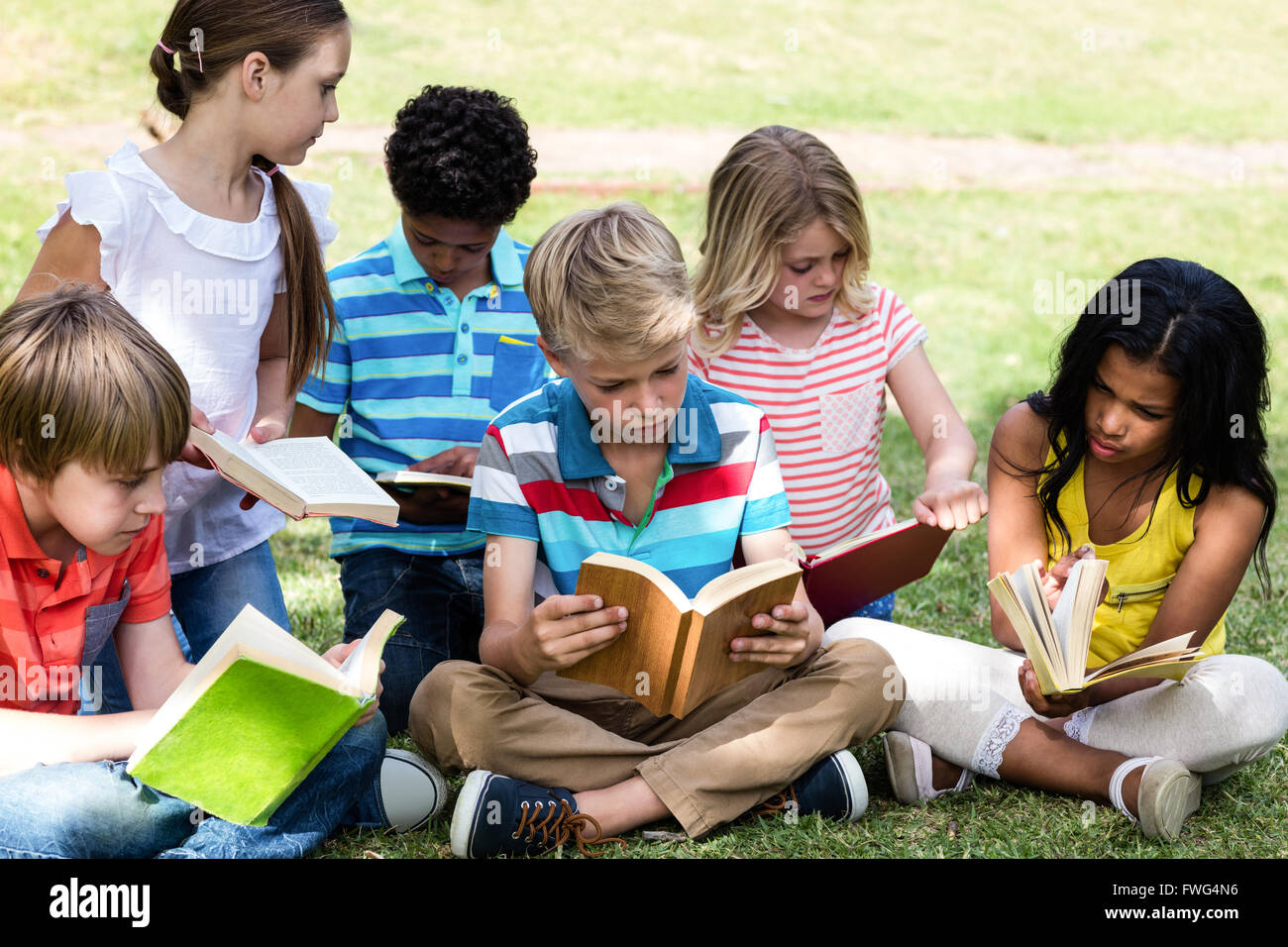 Children reading book in the park Stock Photo - Alamy