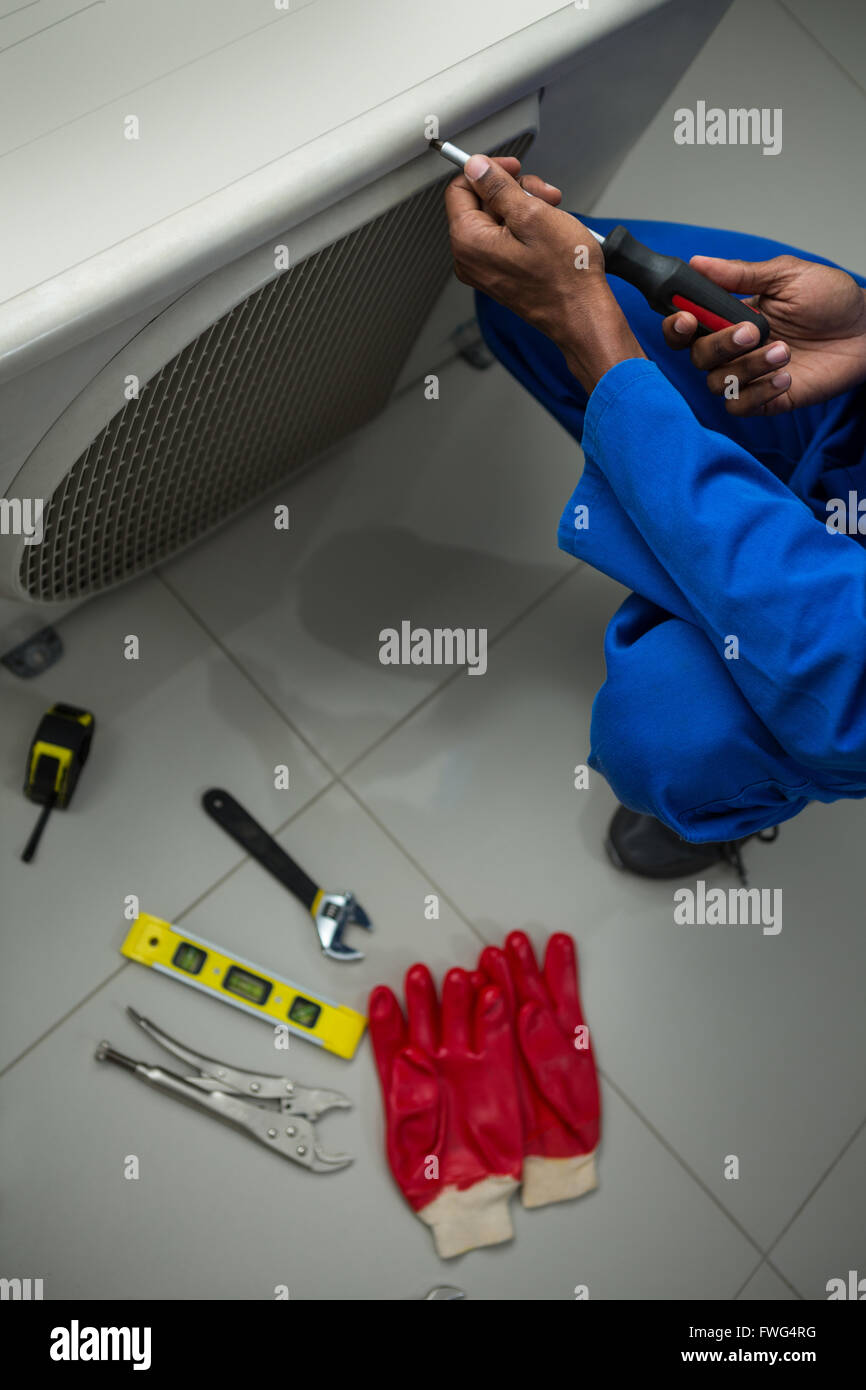 Handyman testing air conditioner with screwdriver Stock Photo - Alamy