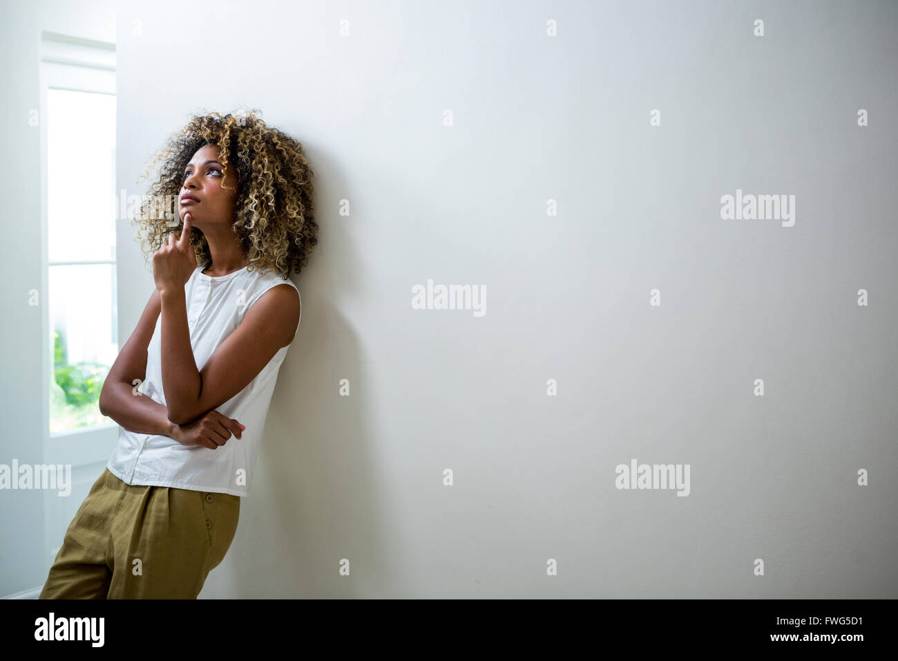 Tensed woman leaning on wall Stock Photo - Alamy