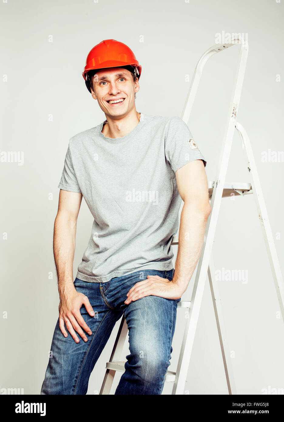 young real hard worker man isolated on white background on ladder ...