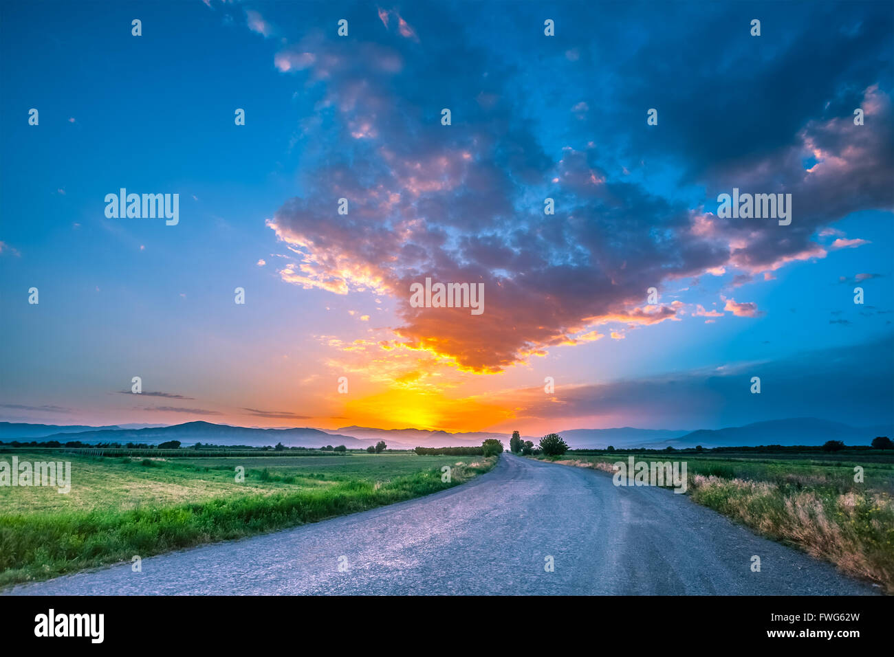 Road on meadow with beautiful sunset sky Stock Photo - Alamy