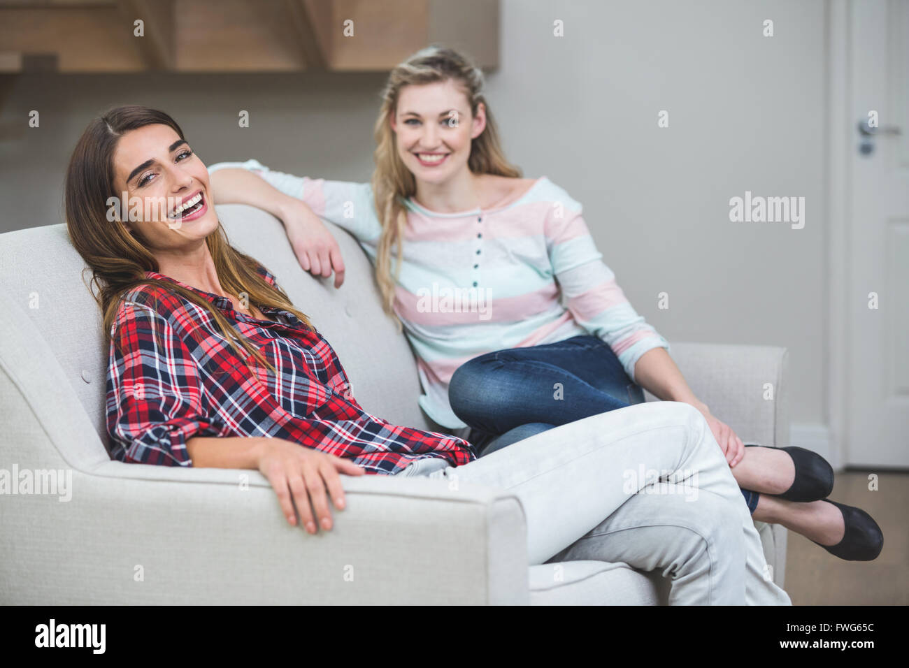 Portrait of two beautiful women sitting on sofa Stock Photo - Alamy