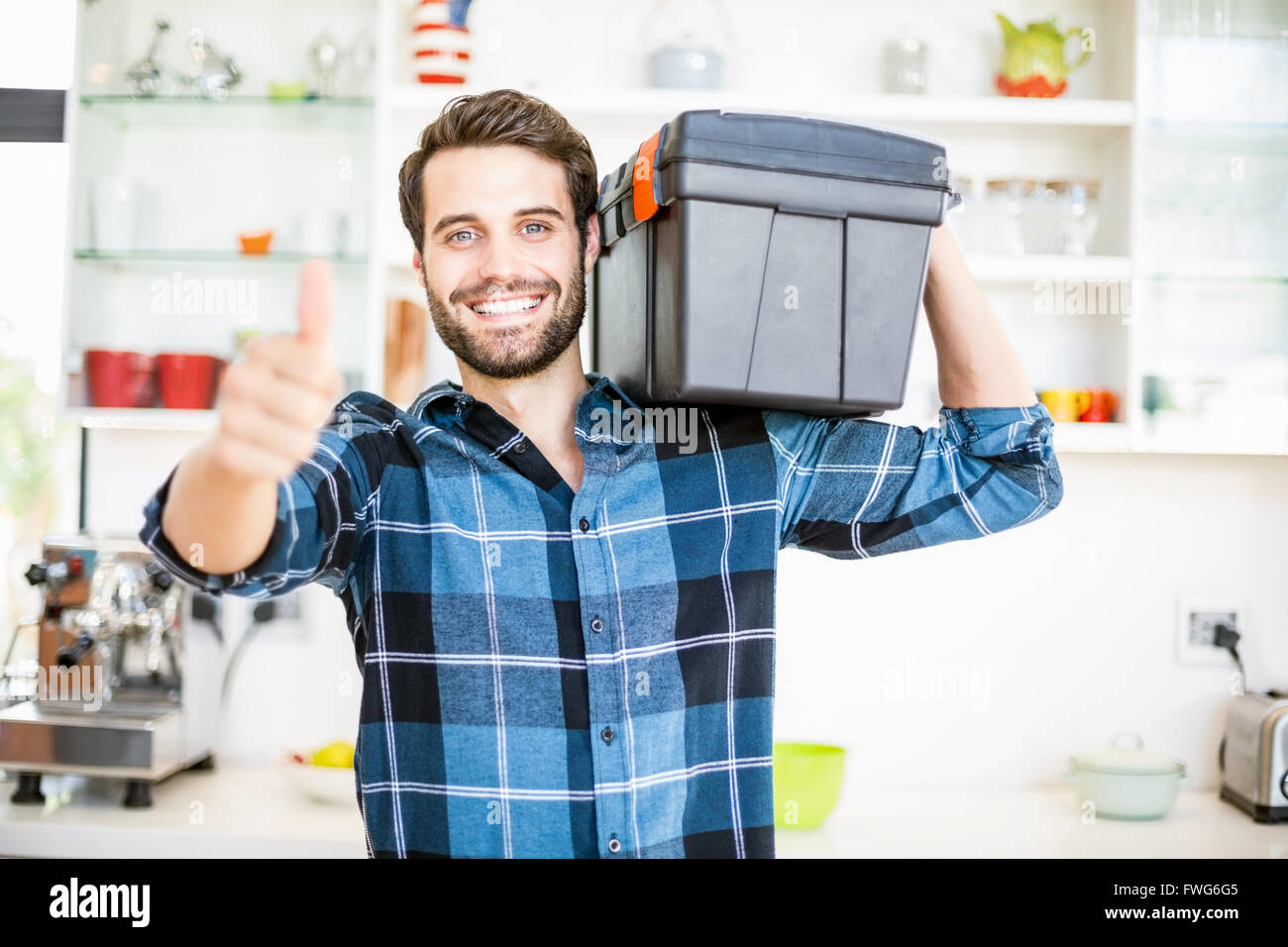 Man carrying tool box giving thumbs up Stock Photo - Alamy