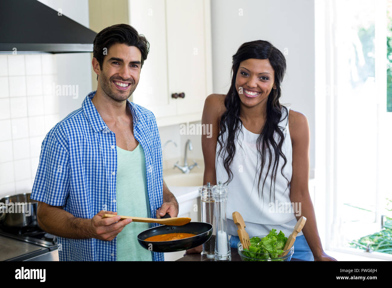 Portrait of young couple cooking food together in kitchen Stock Photo ...