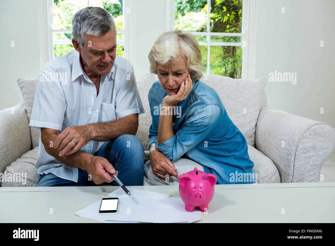 Senior man discussing with wife regarding savings on sofa Stock Photo ...