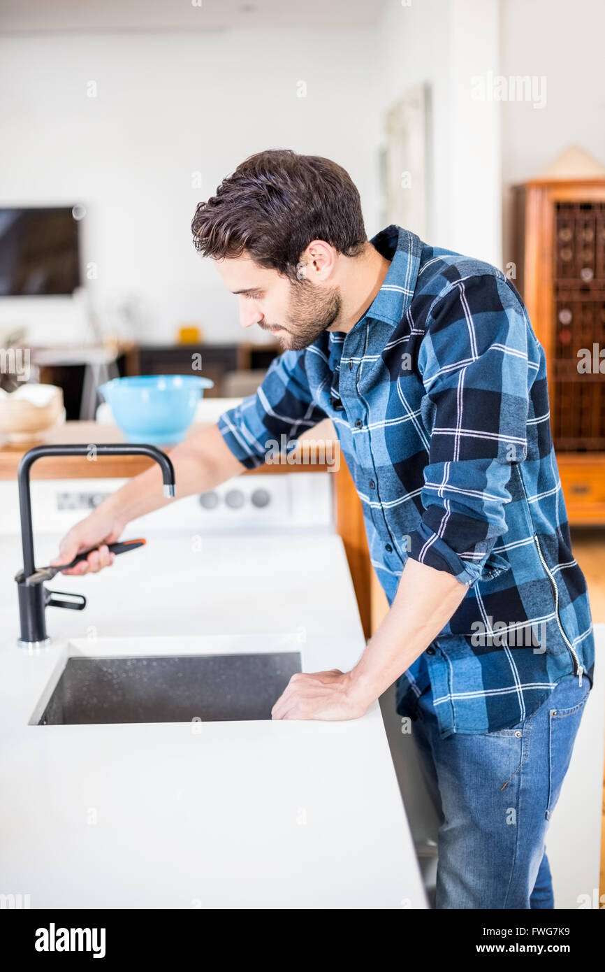 Man fixing tap with tool in the kitchen Stock Photo - Alamy