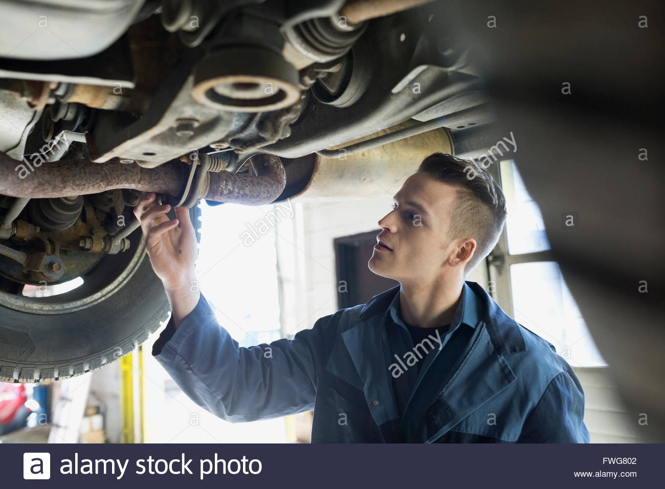Mechanic working under car in auto repair shop Stock Photo - Alamy