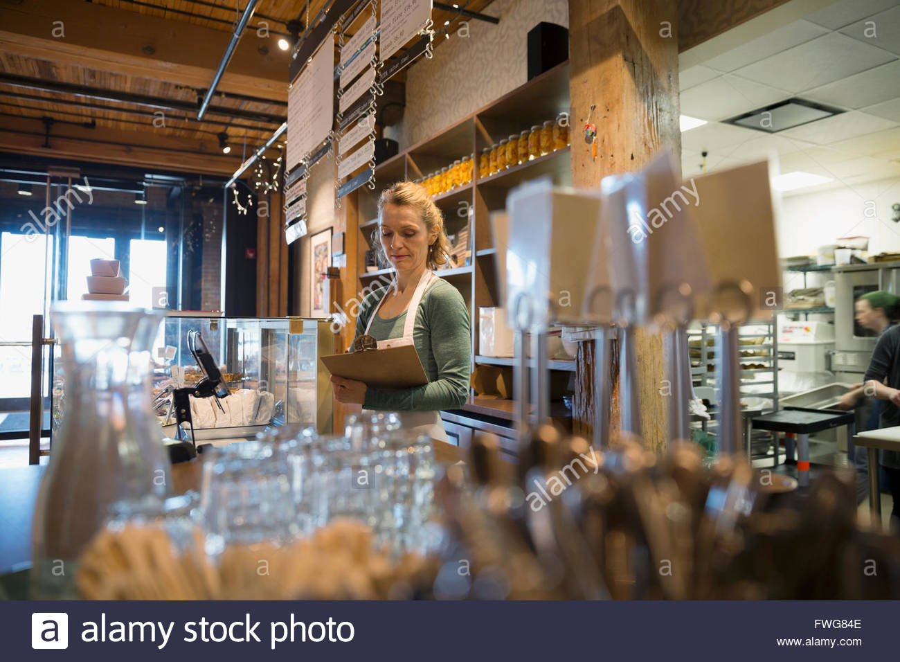 Bakery owner with clipboard behind the counter Stock Photo - Alamy