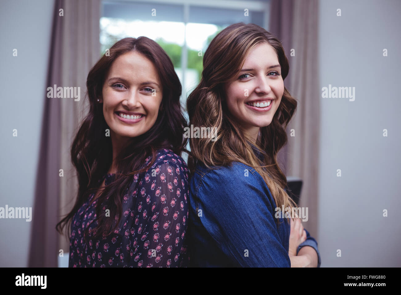 Portrait of beautiful women standing back to back Stock Photo - Alamy
