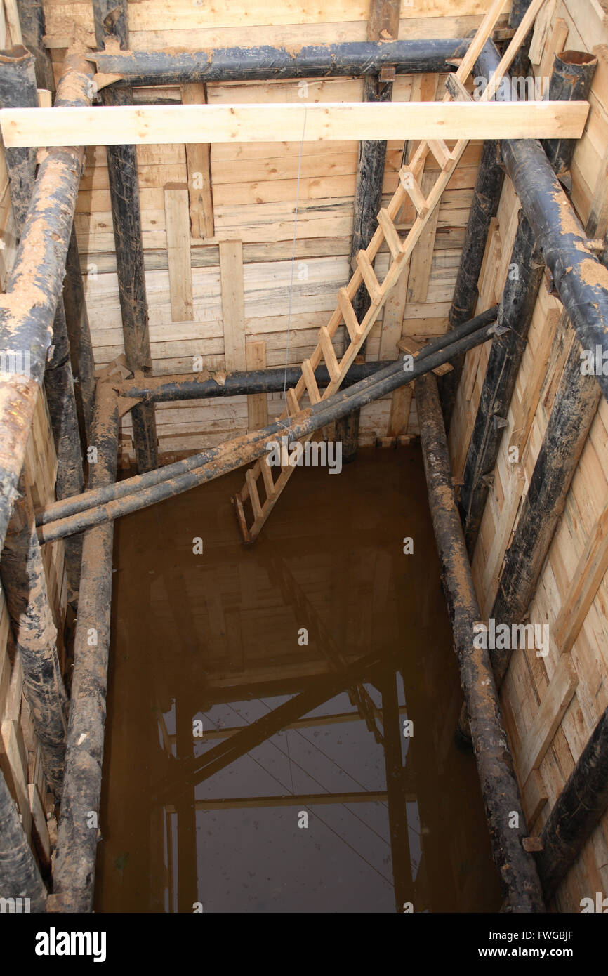 Pipeline mending. Deep pit in land with wooden ladder and pipes Stock ...