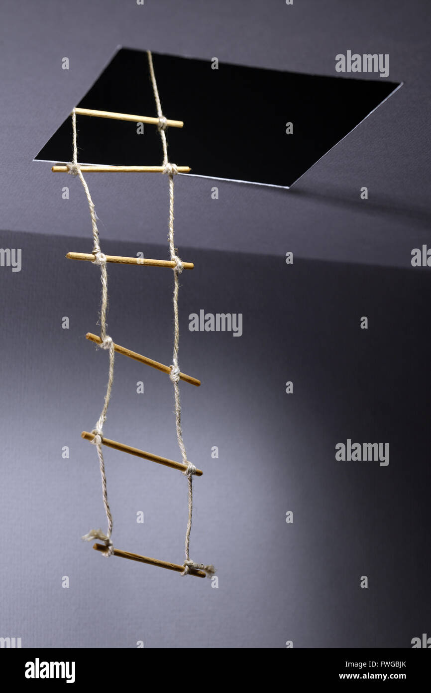 Escape concept. Rope ladder inside hatch in ceiling Stock Photo - Alamy