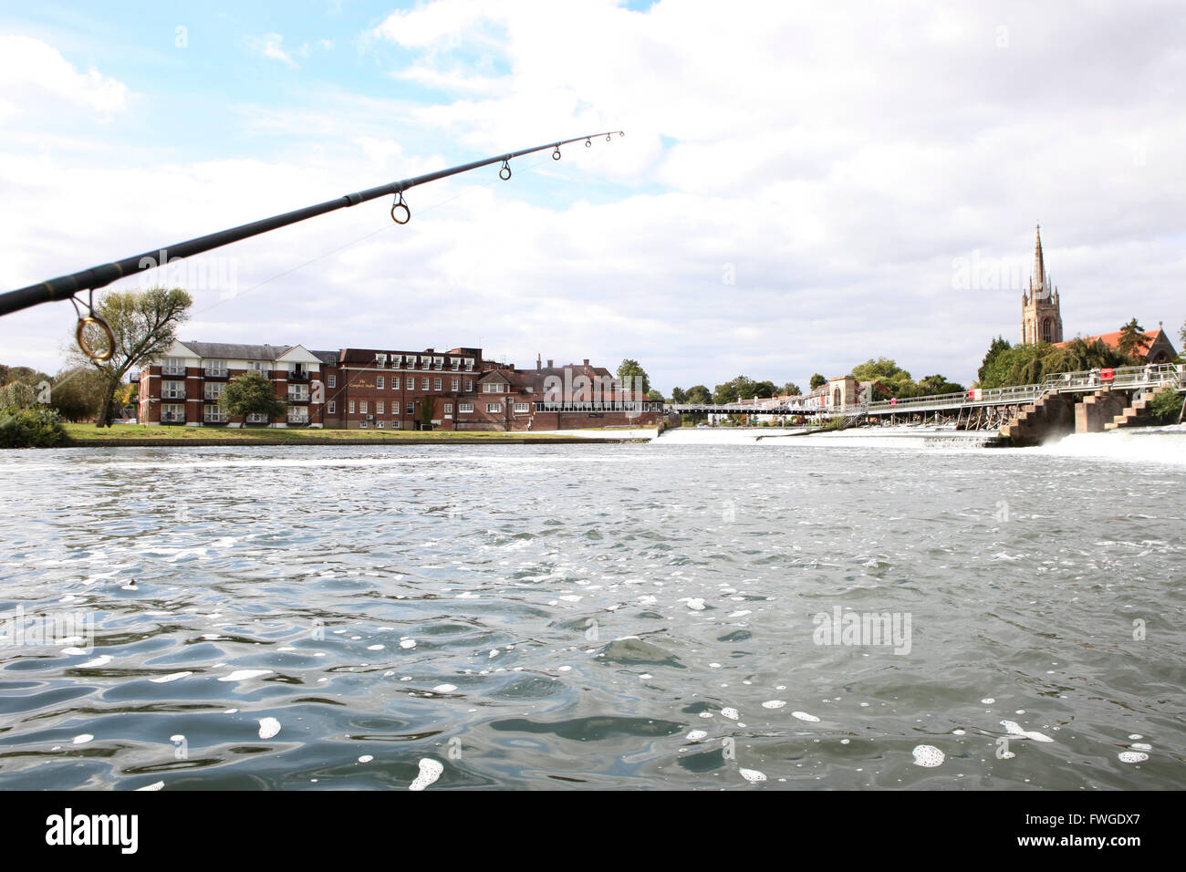 A fishing rod and line over a stretch of water by a weir and bridge ...