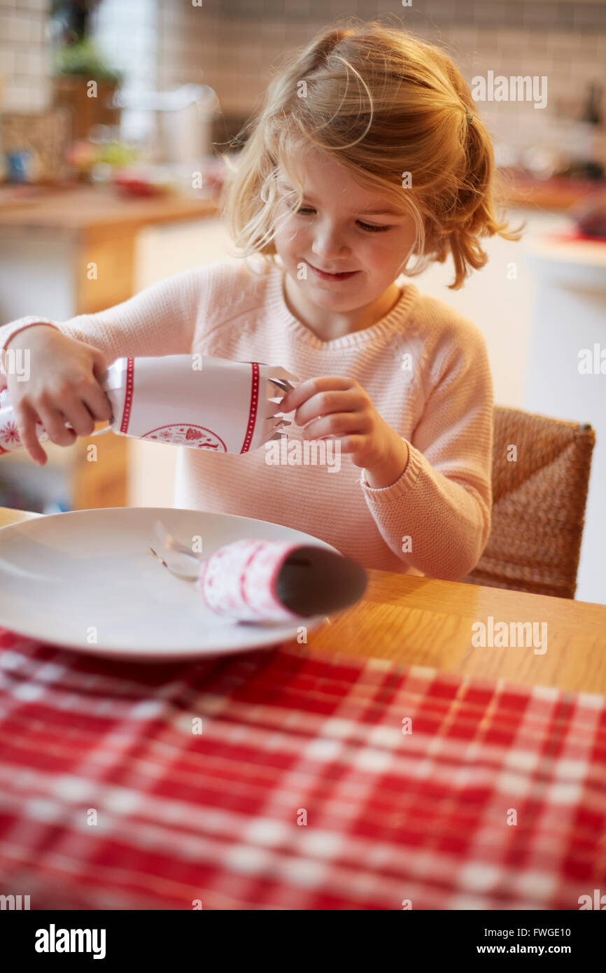 A girl opening a Christmas cracker at a table Stock Photo - Alamy