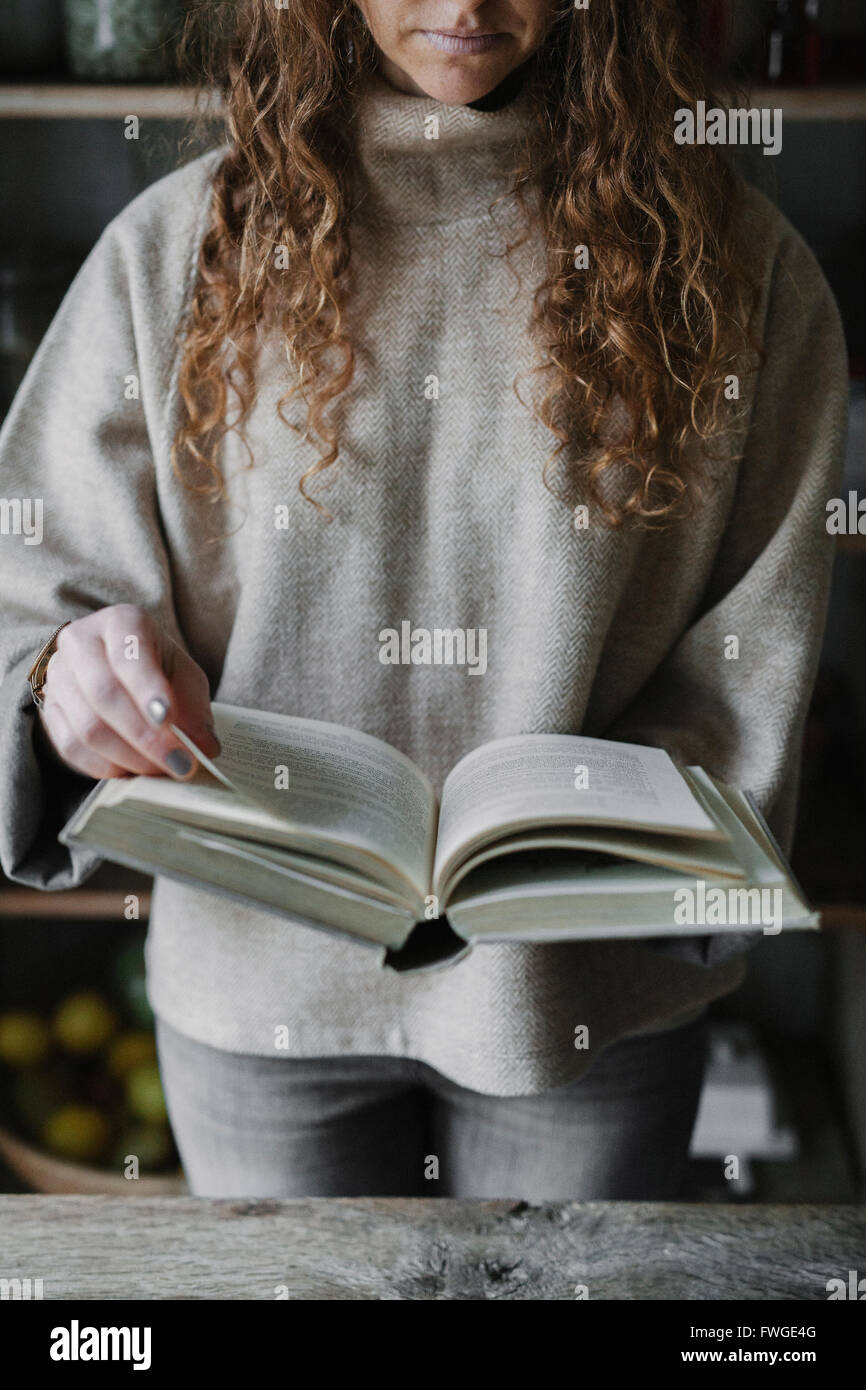 A woman reading from a recipe book in a kitchen Stock Photo - Alamy