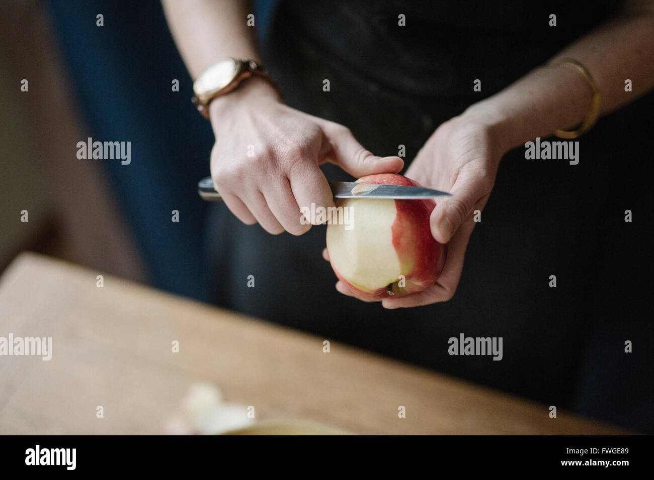 A woman in a blue apron peeling an apple with a knife Stock Photo - Alamy